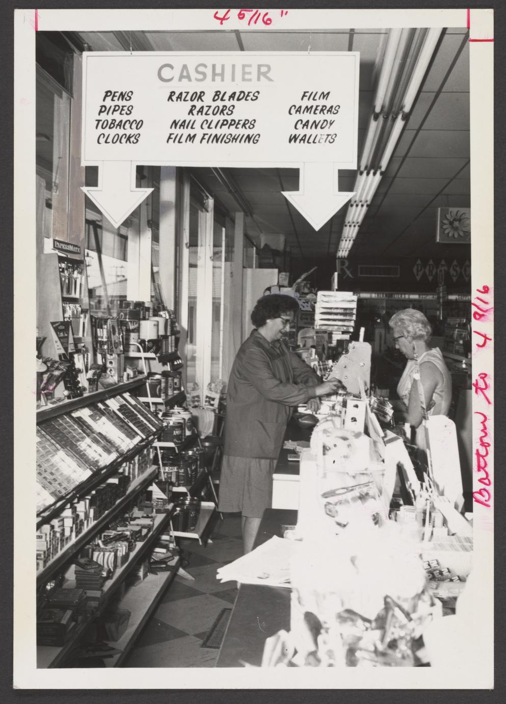 ‎A salesclerk assists a customer below a large store sign promoting ...